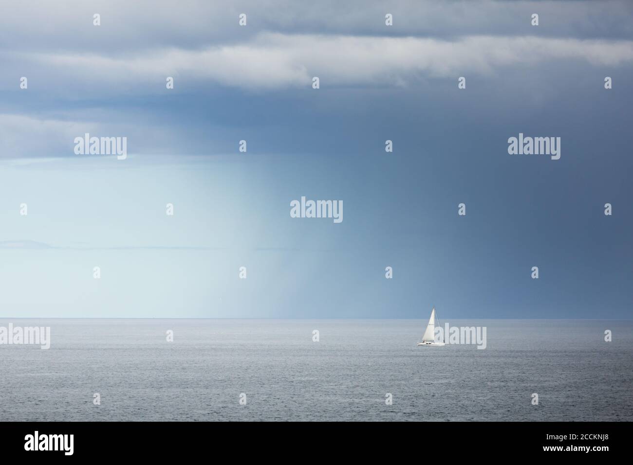 Sail boat out at sea under a rain storm front cloud off the ...