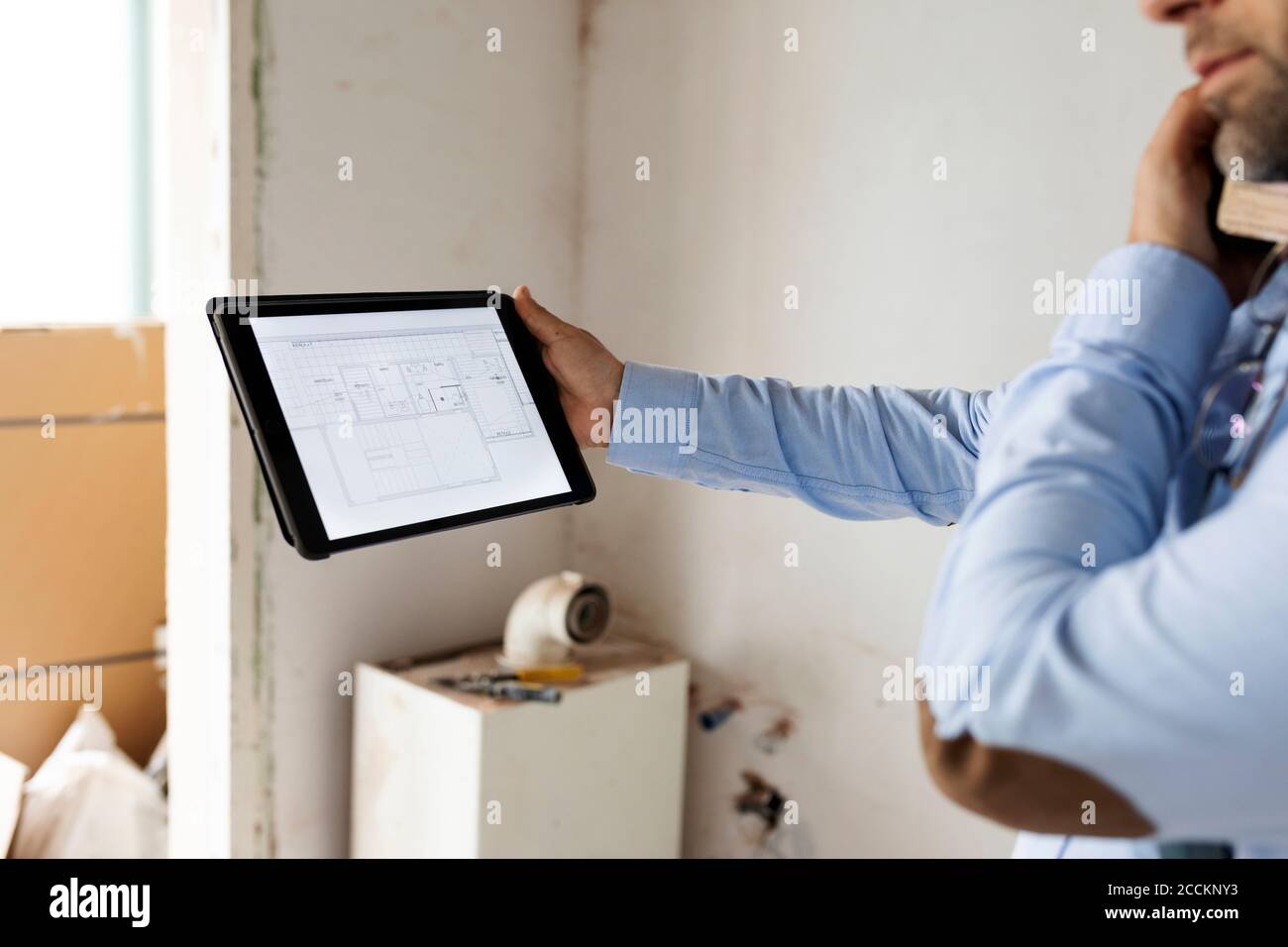 Architect holding tablet with construction plan Stock Photo - Alamy
