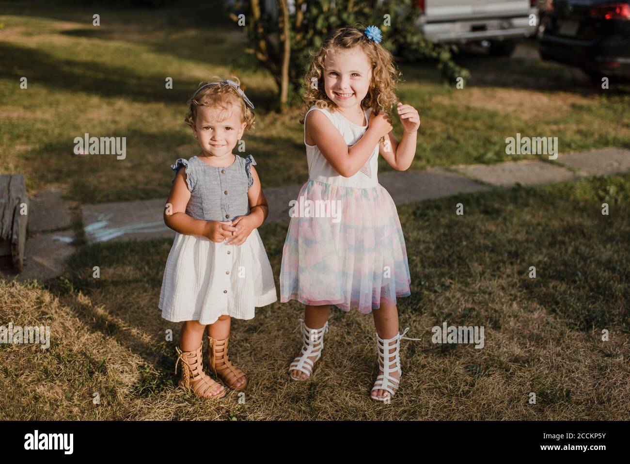 Portrait of two cute sisters standing on a meadow Stock Photo - Alamy