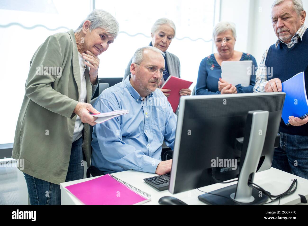 Active seniors attending computer course, watching instructor and ...