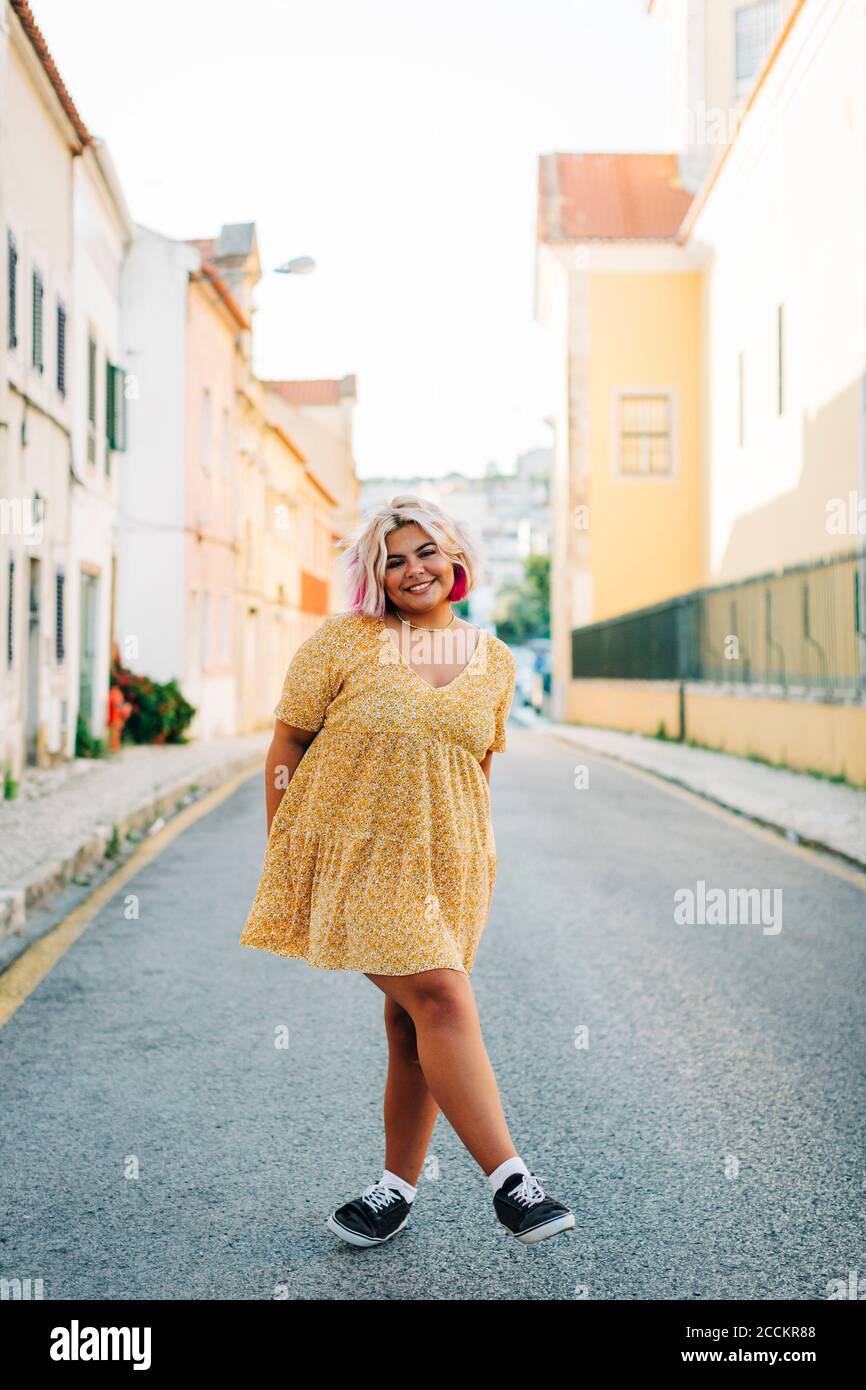 Smiling plus size woman standing with crossed leg on road Stock Photo ...
