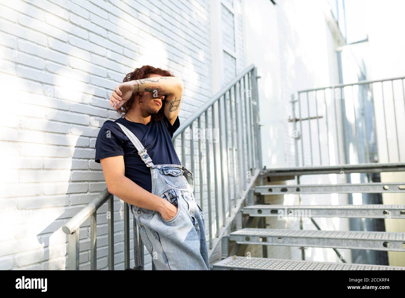 Man hiding face while standing on staircase Stock Photo - Alamy