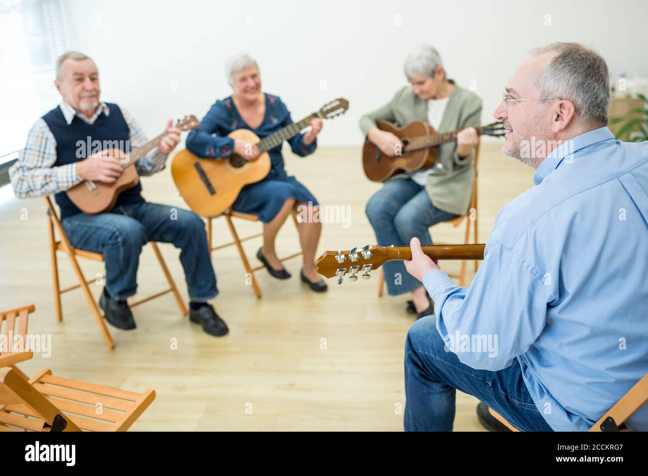 Seniors in retirement home attending guitar class, making music Stock ...