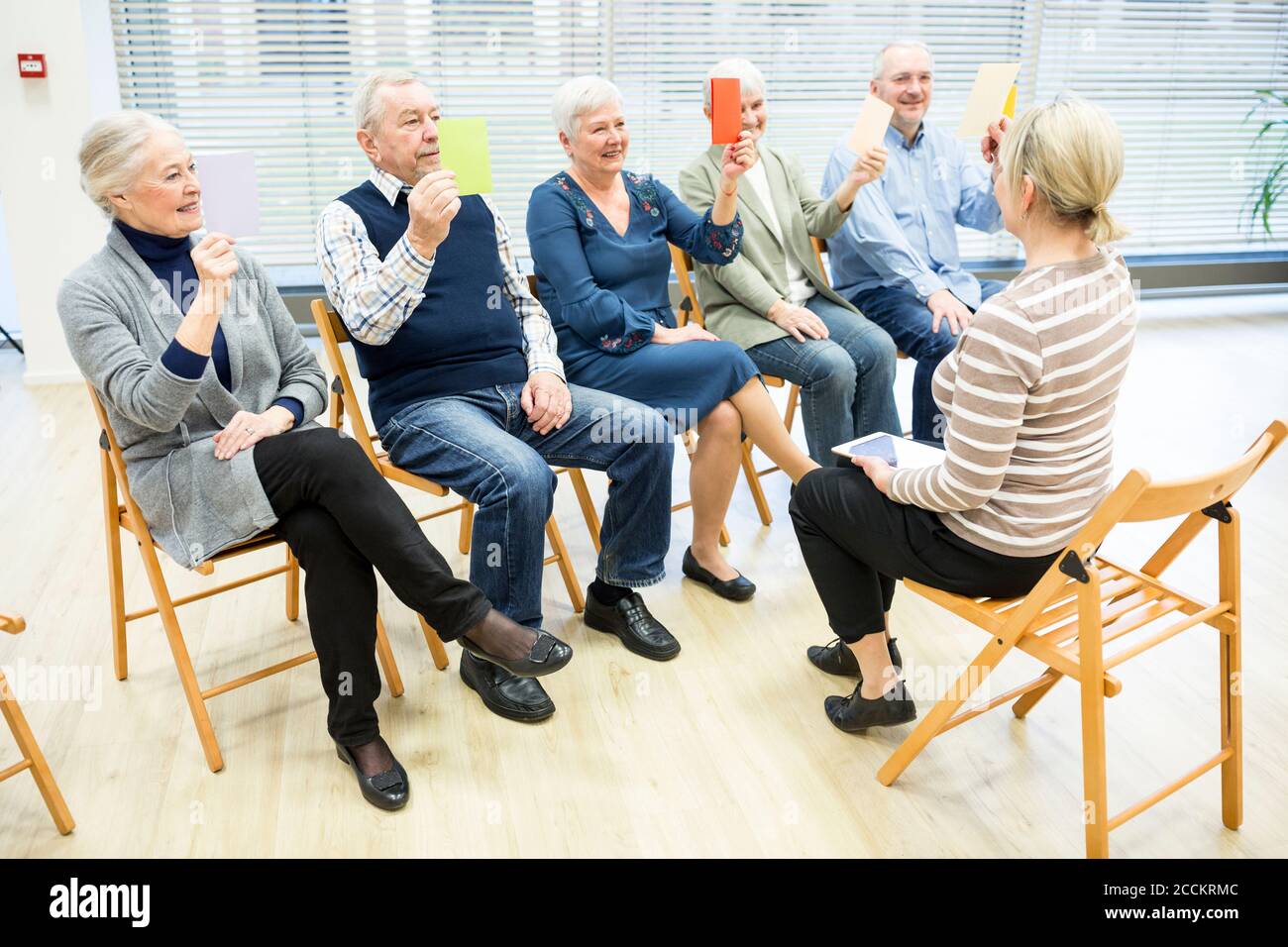 Seniors in retirement home attending group therapy using colorful paper ...