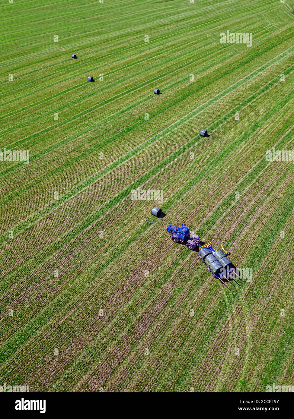 Aerial view of tractor collecting hay bales in field Stock Photo - Alamy