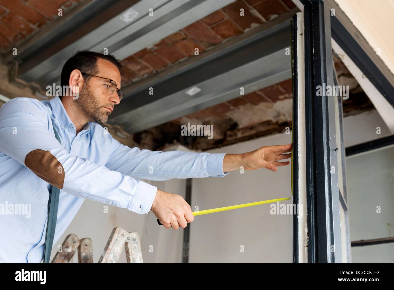 Architect using tape measure on window frame in a house under ...