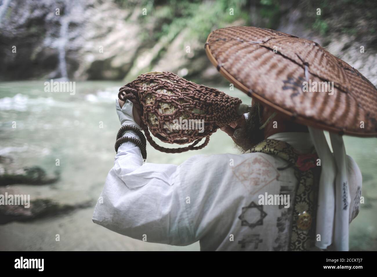 European yamabushi monk in traditional shugendo robe blowing the ...