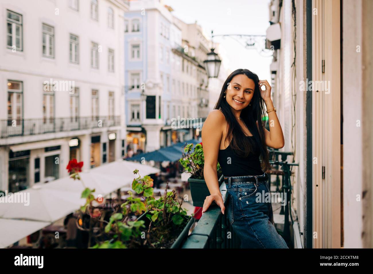 Smiling young woman leaning on balcony railing Stock Photo - Alamy