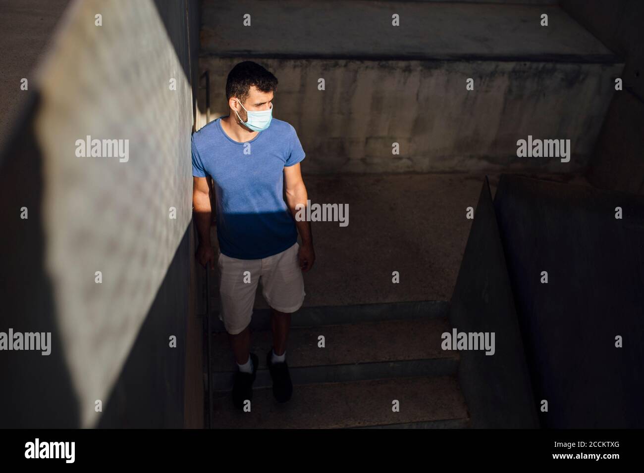 Young man wearing mask standing on steps by wall Stock Photo - Alamy