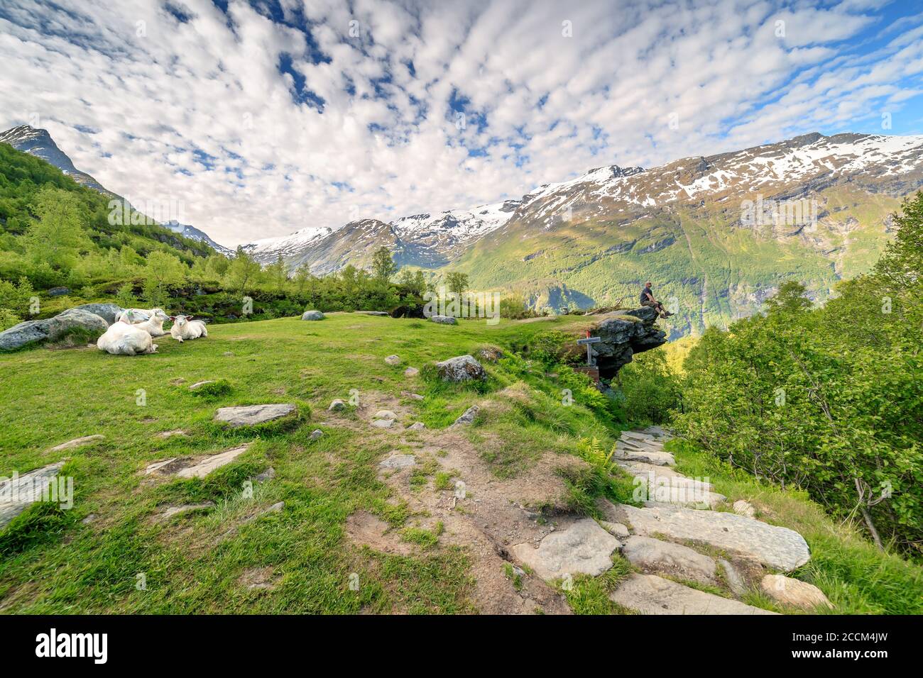 GEIRANGER, NORWAY - 2016 JUNE 13. One man sitting on the cliff to view ...