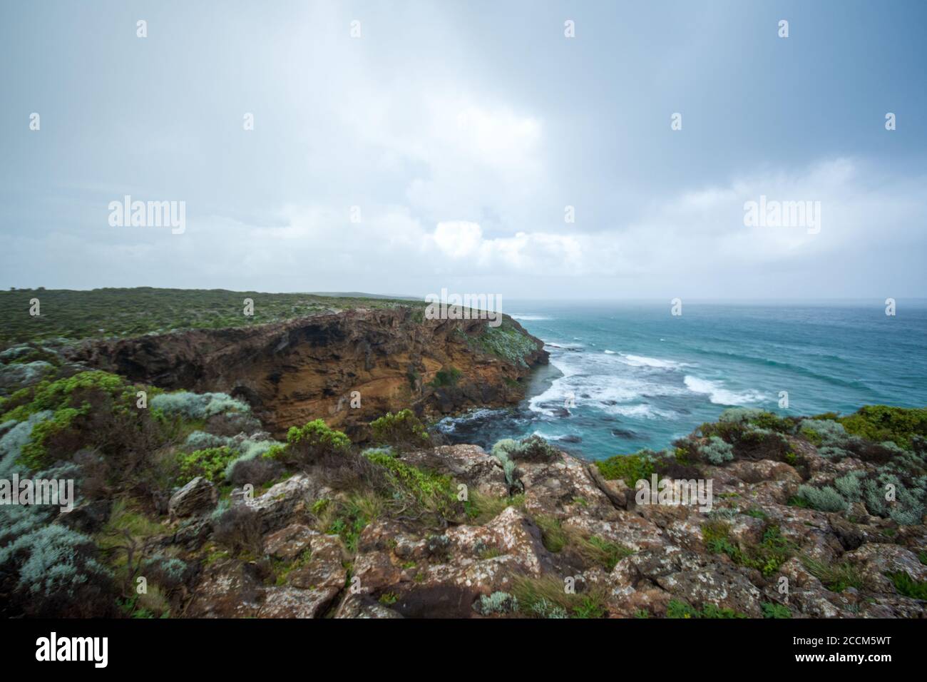 Beautiful ocean waves hitting the rocky cliffs under the cloudy sky ...