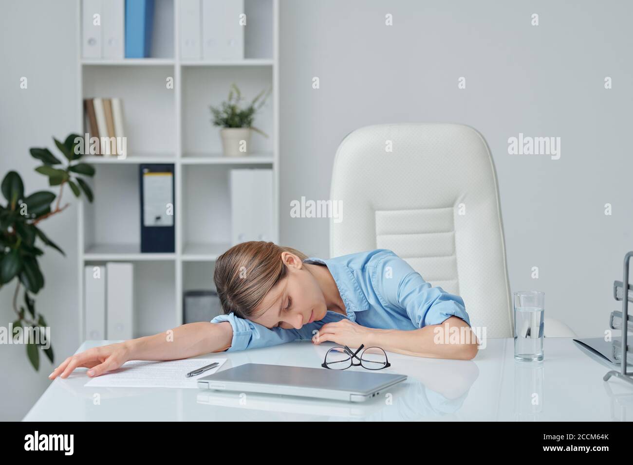 Tired contemporary young office manager lying on desk and napping after ...