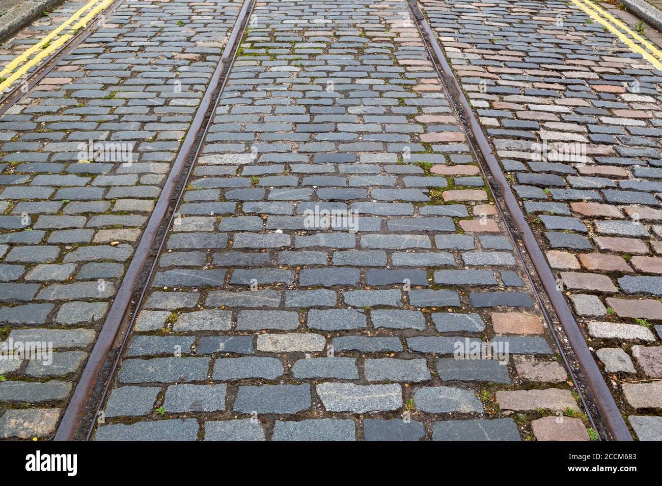 A cobbled street with tram line running through the centre of the road ...