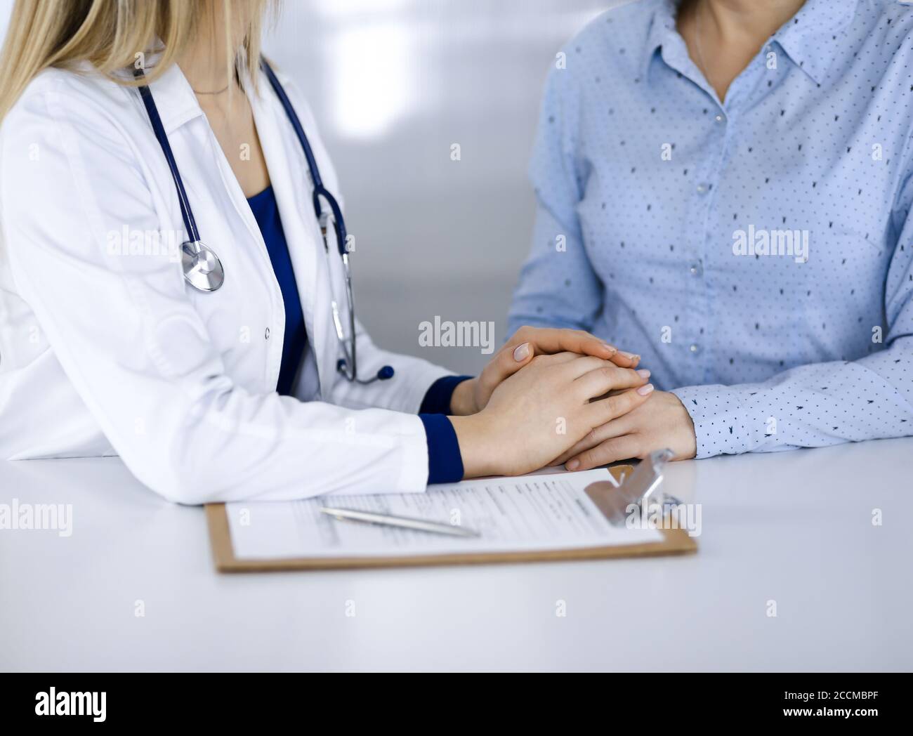 Unknown woman-doctor is holding her patient's hands to reassure a ...