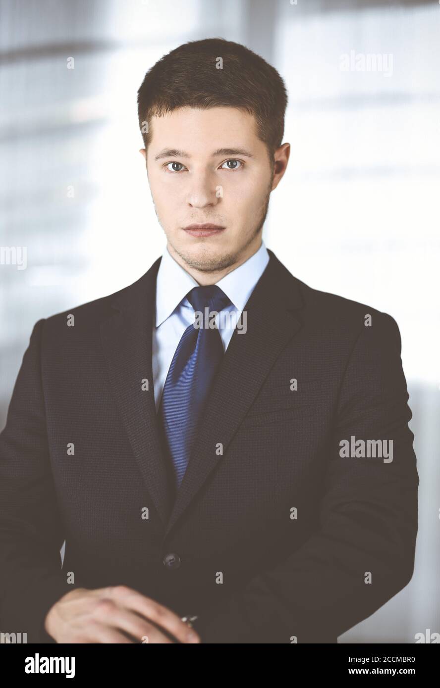 Young businessman wearing suit and tie, while standing in the office ...
