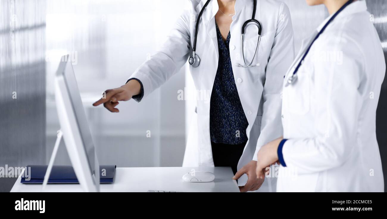 Two female physicians are discussing medical therapy, while standing at ...