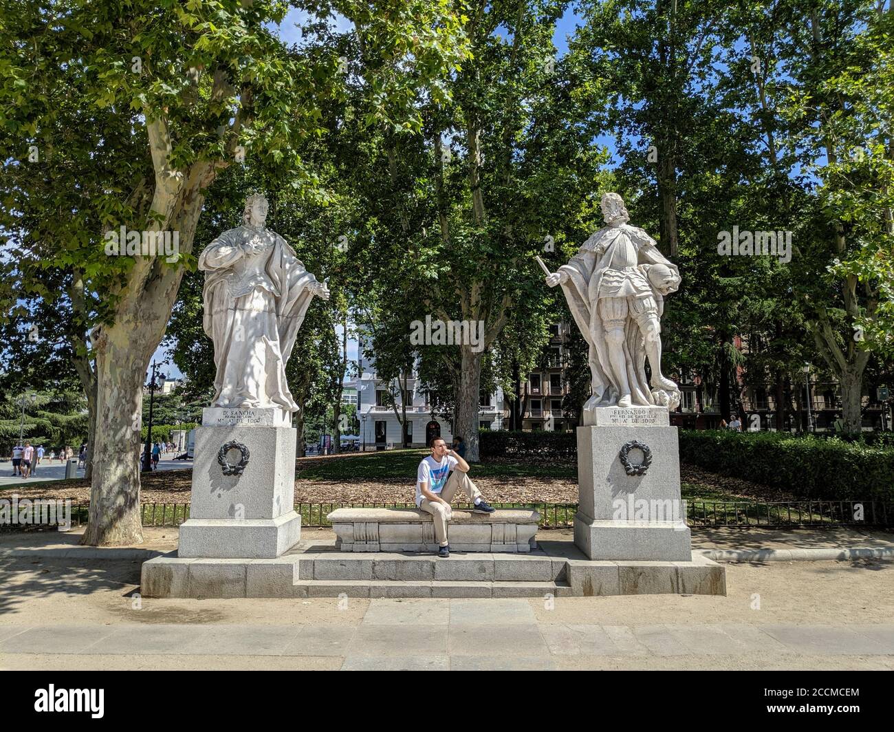 Person sitting between two statues at the Plaza de Oriente, Madrid ...