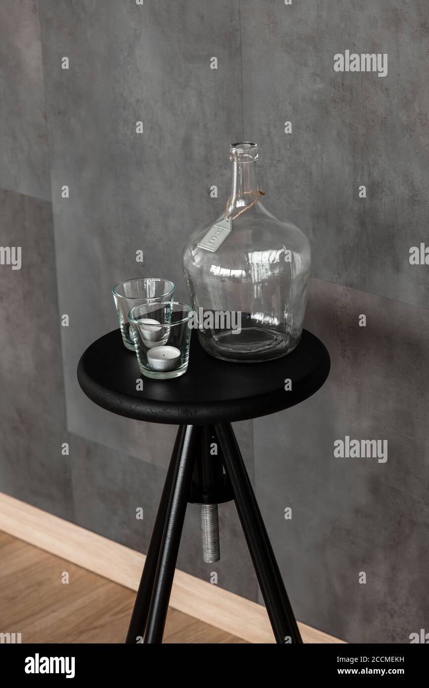 black metal stool with glass decanter and various containers in front ...