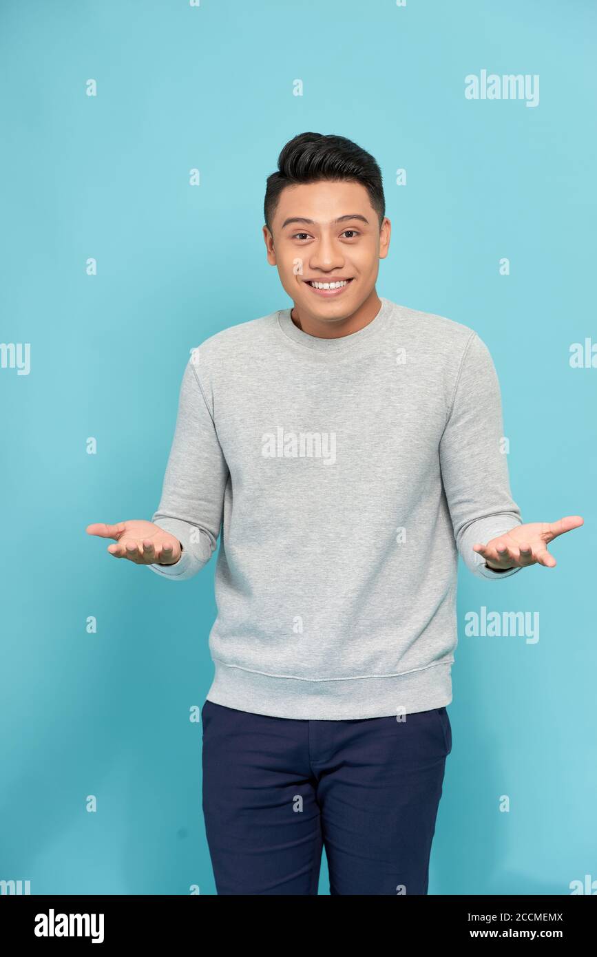 Young happy handsome Asian man raising his hands with open palms ...