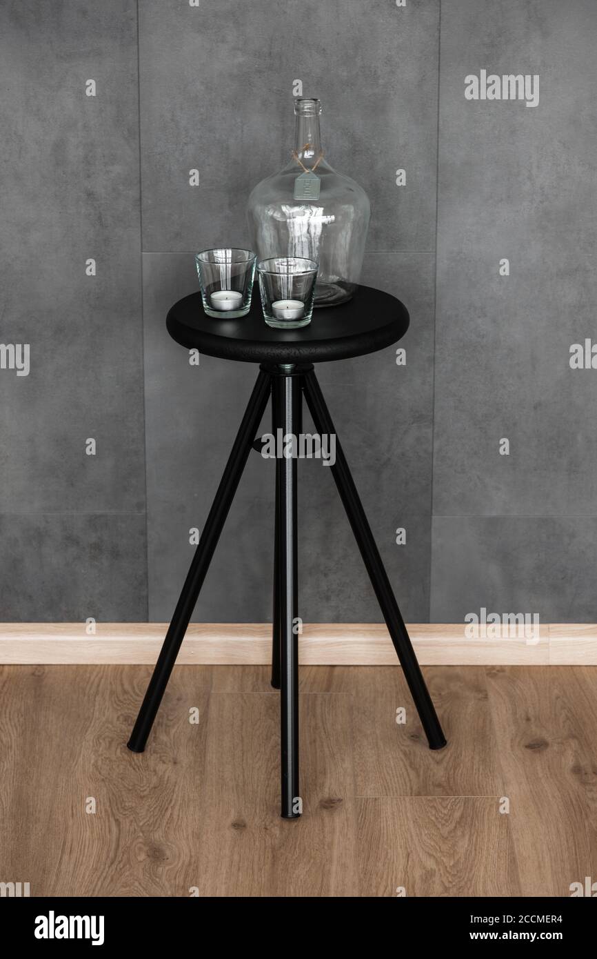 black metal stool with glass decanter and various containers in front ...