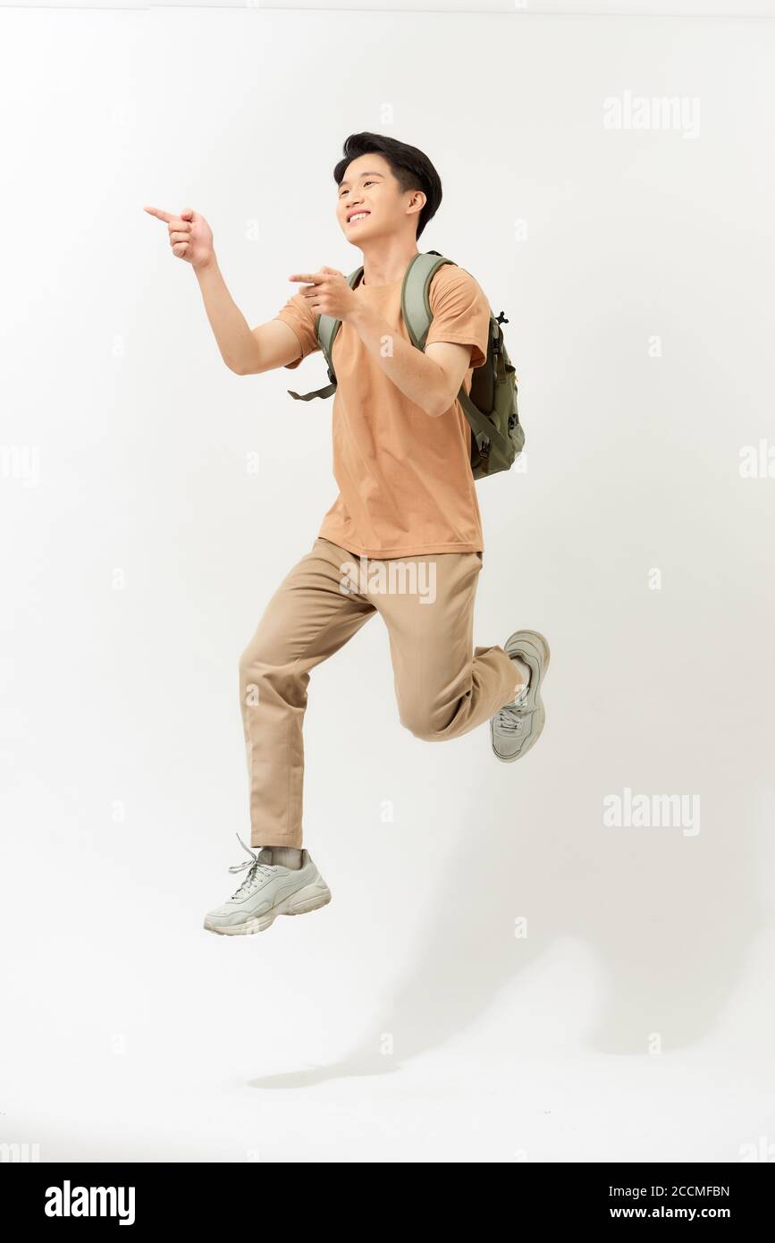 Young cheerful energetic handsome Asian man jumping with hands pointing ...