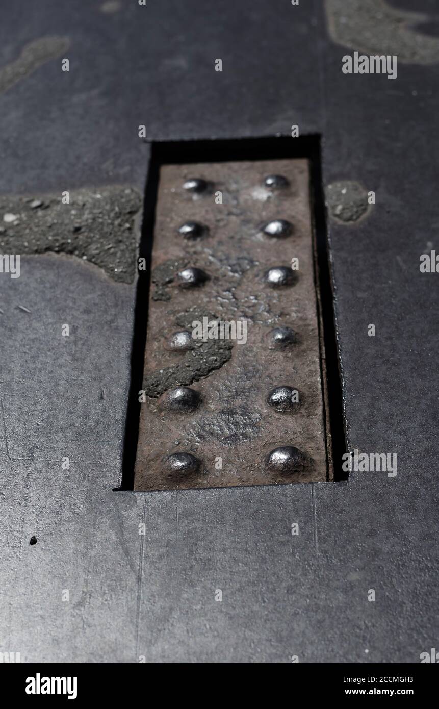 Old rusty rectangular plate with rivets on a metal surface. Fragment of ...