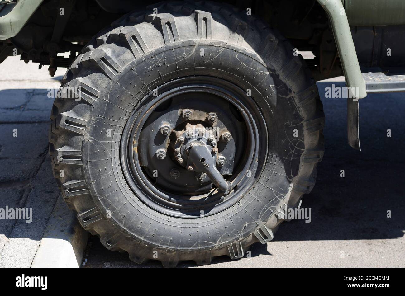 Fragment of a military truck close-up. Dirty wheel of a large all ...