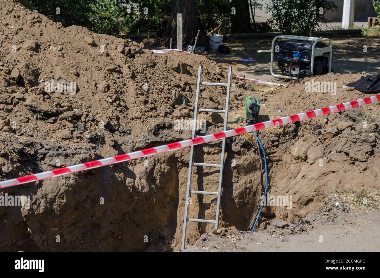 Welding machine, generator and ladder next to the dug trench. The place ...