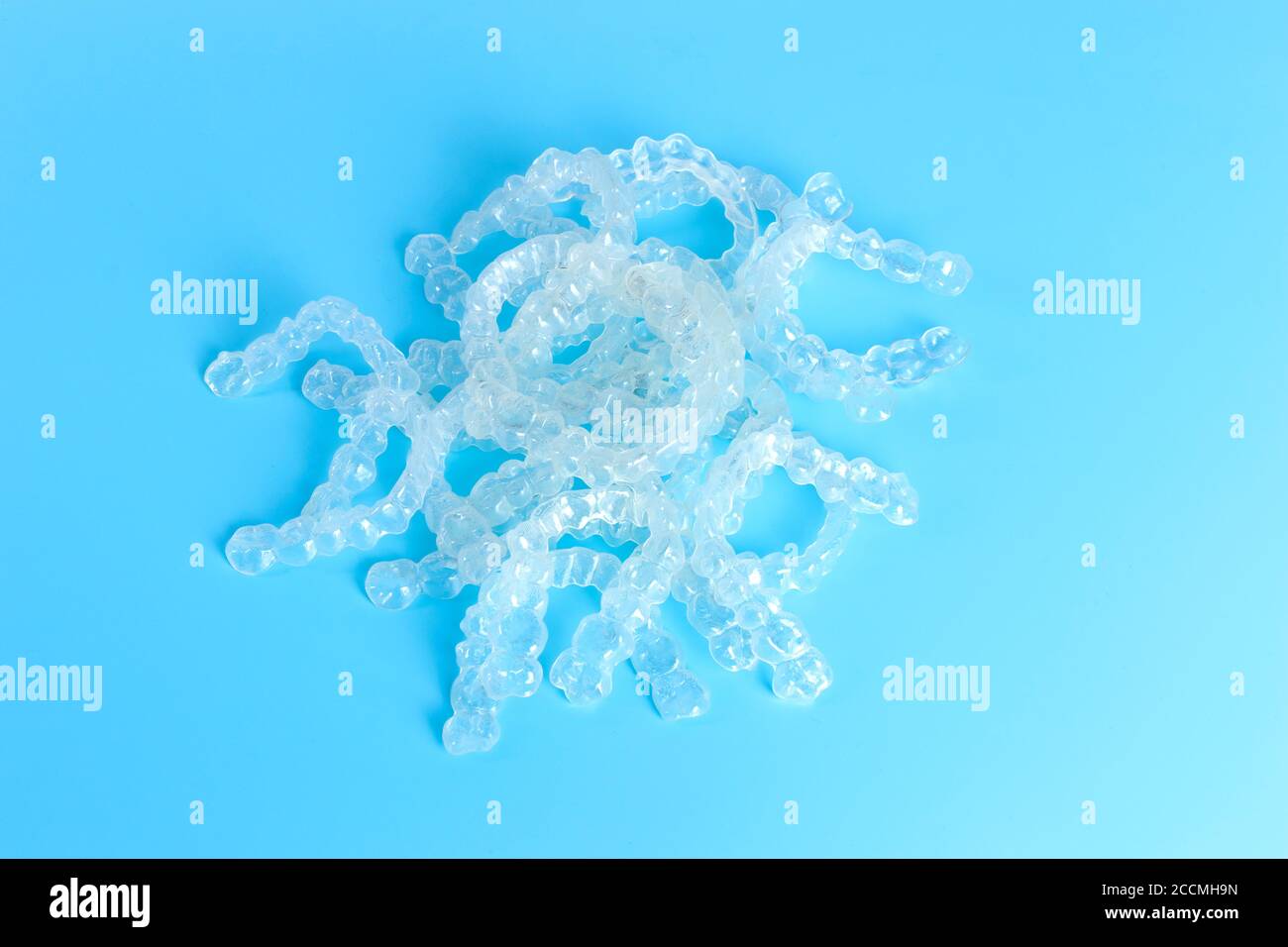 Invisalign transparent brackets pile on blue background Stock Photo - Alamy