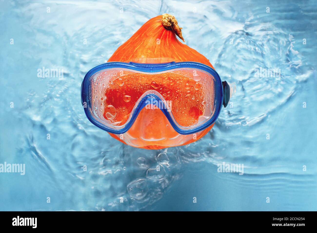Orange pumpkin swimmer in a mask in blue water. Halloween concept Stock ...