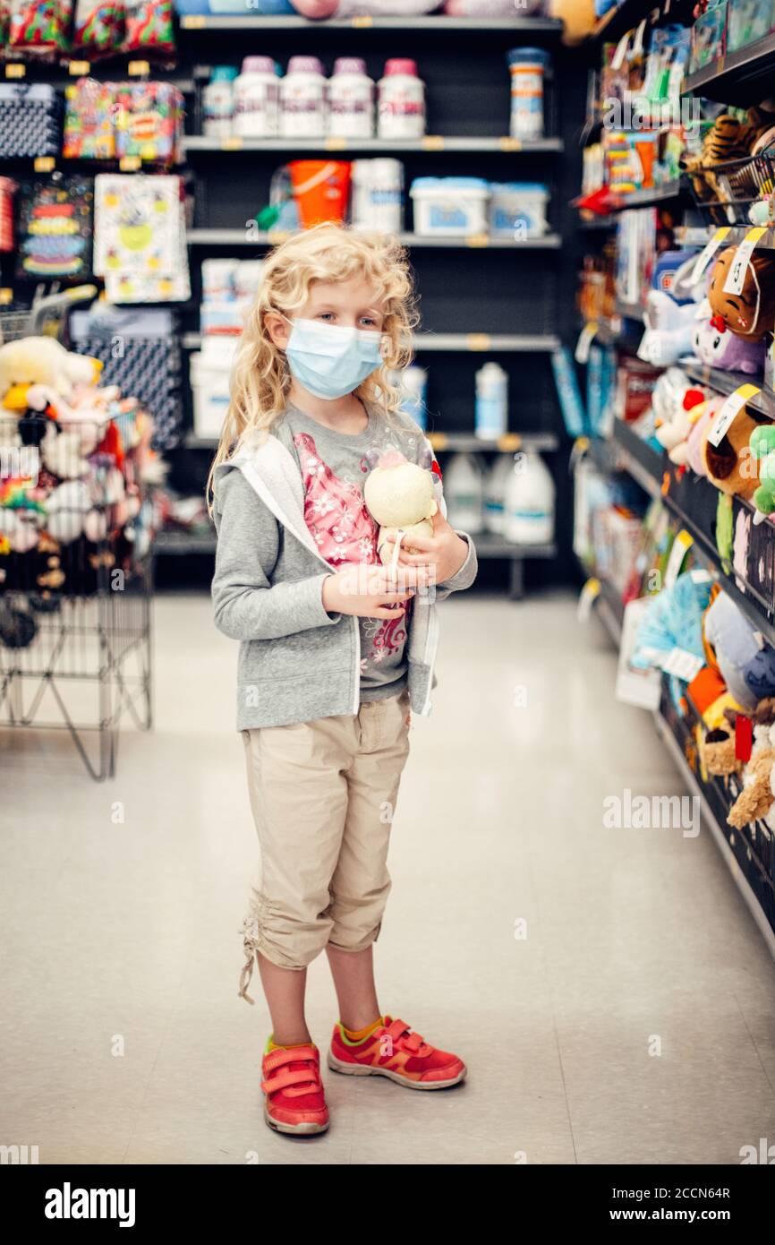 A new normal. Caucasian blonde girl in sanitary face mask shopping at ...