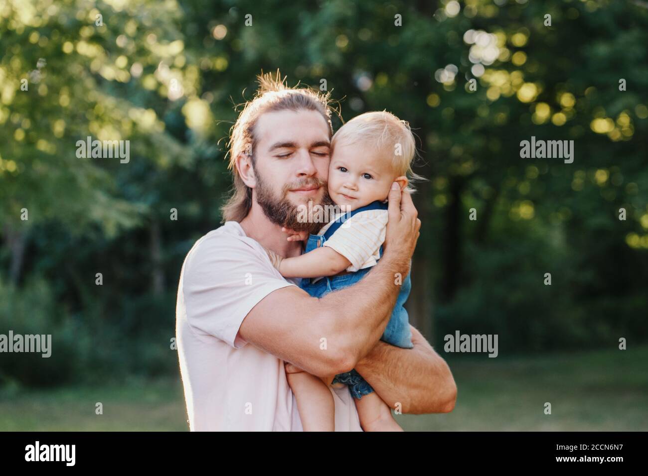Proud father hugging embracing toddler baby boy outdoor. Young parent ...