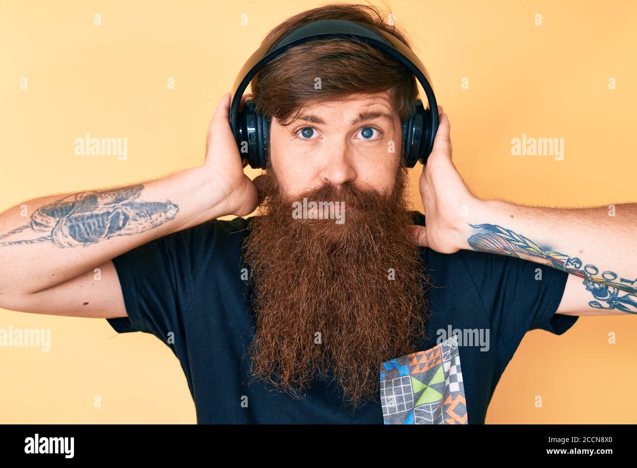 Handsome Young Red Head Man With Long Beard Listening To Music Using