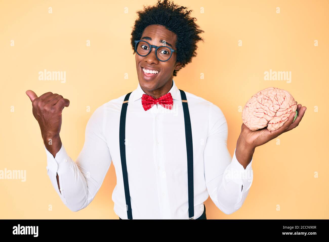 Handsome african american nerd man with afro hair holding brain ...