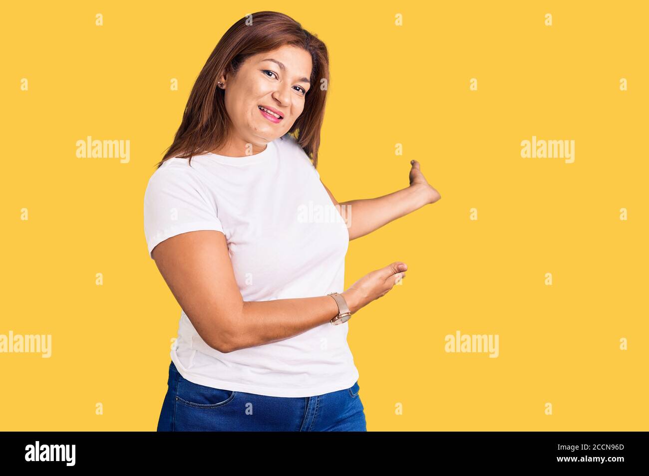 Middle age latin woman wearing casual white tshirt inviting to enter ...