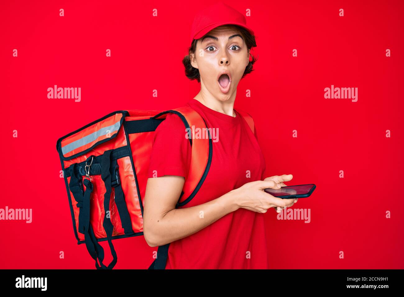 Young hispanic woman holding delivery box calling assistance afraid and ...