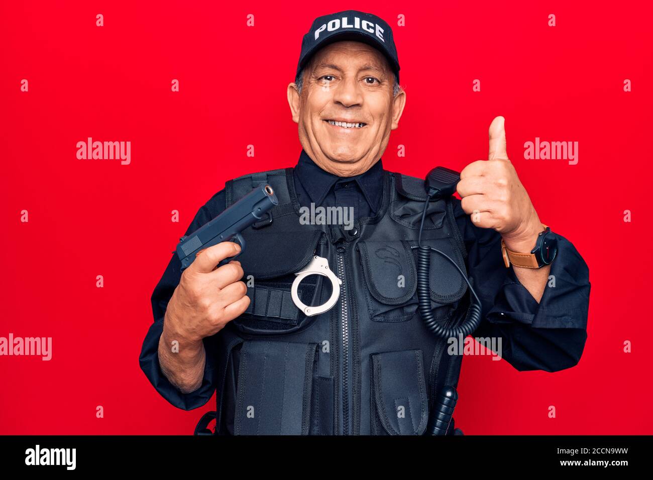 Senior man with grey hair wearing police uniform holding gun smiling ...