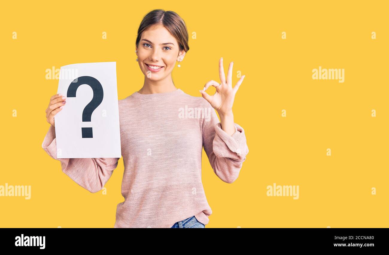 Beautiful caucasian woman with blonde hair holding question mark doing ...