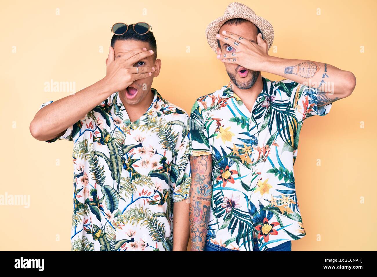 Young gay couple of two men wearing summer hat and hawaiian shirt ...