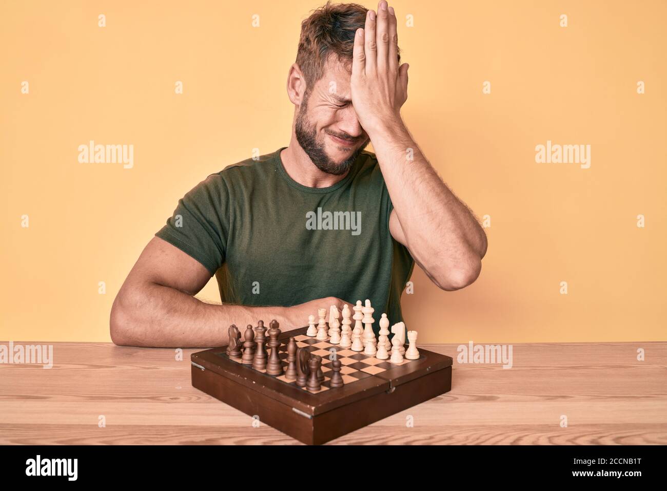 Young caucasian man playing chess sitting on the table surprised with ...