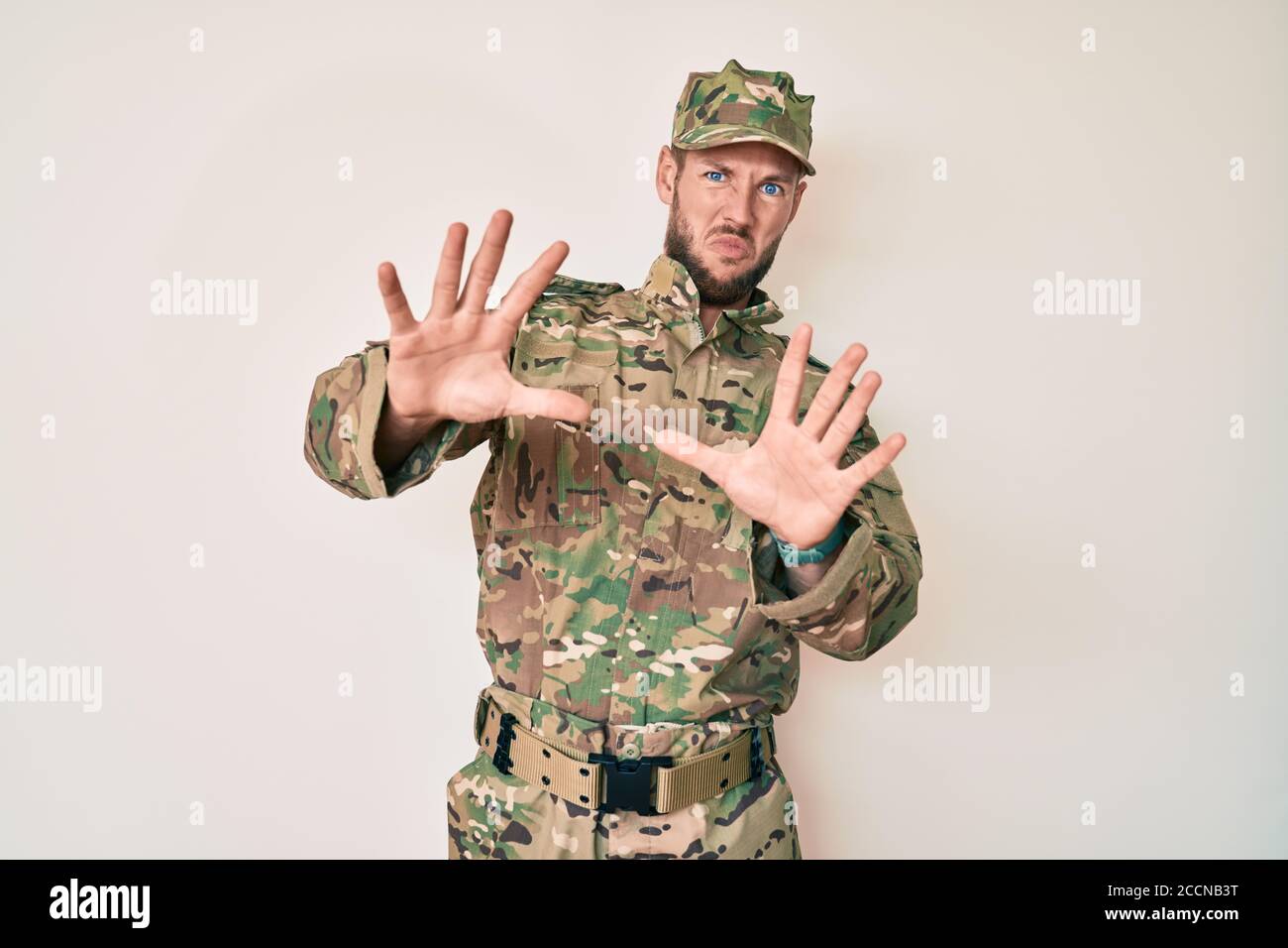 Young caucasian man wearing camouflage army uniform afraid and ...