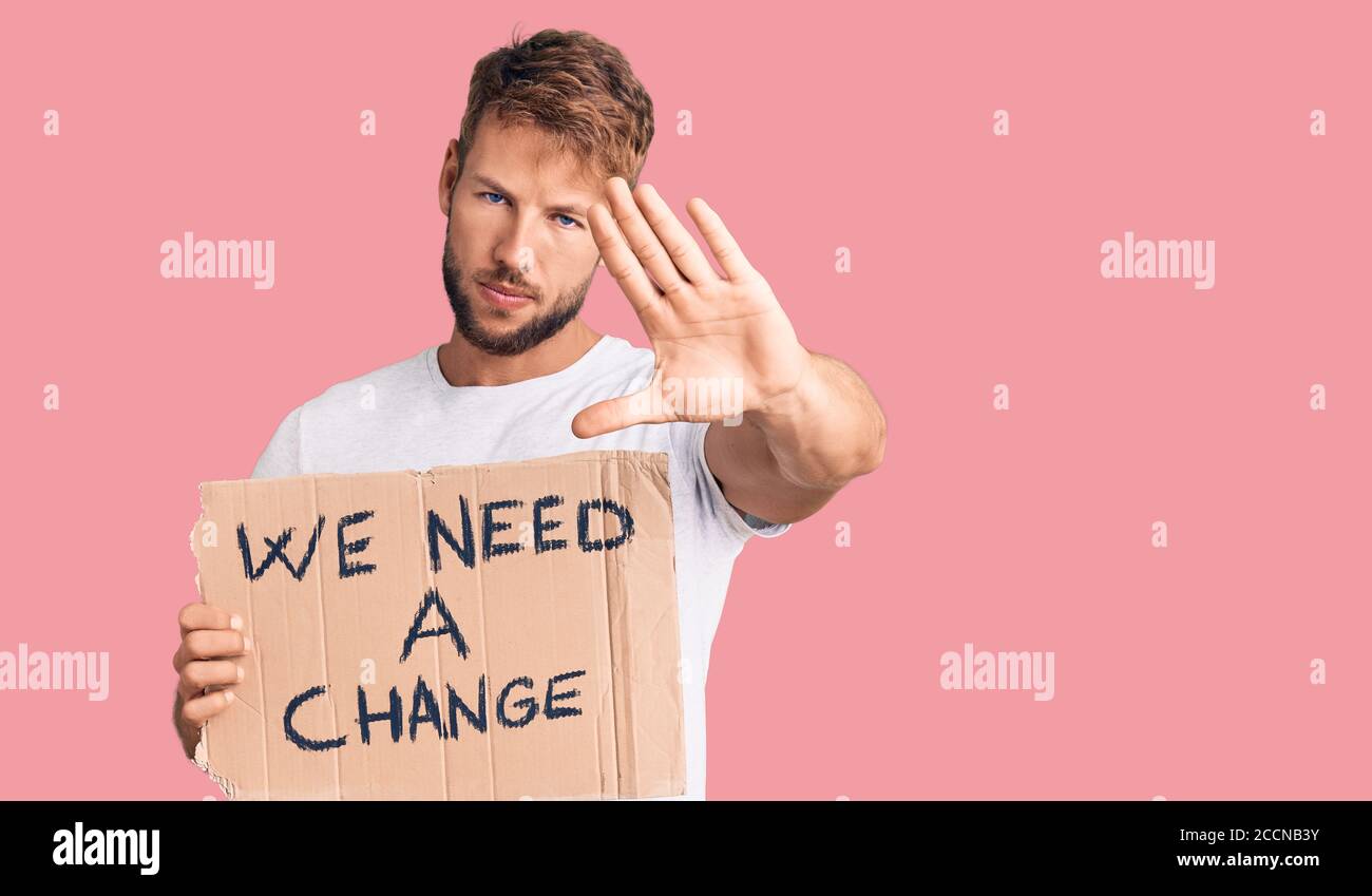 Young caucasian man holding we need a change banner with open hand ...