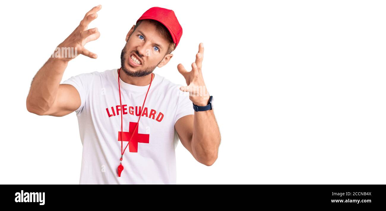 Young caucasian man wearing lifeguard t shirt holding whistle shouting ...