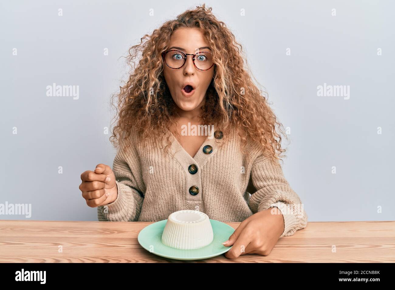 Beautiful caucasian teenager girl eating fresh white cheese scared and ...