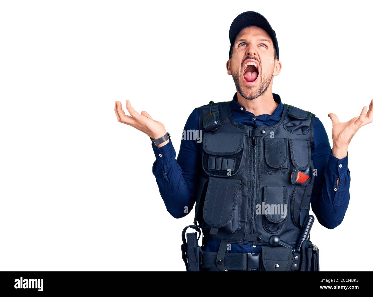 Young handsome man wearing police uniform crazy and mad shouting and ...