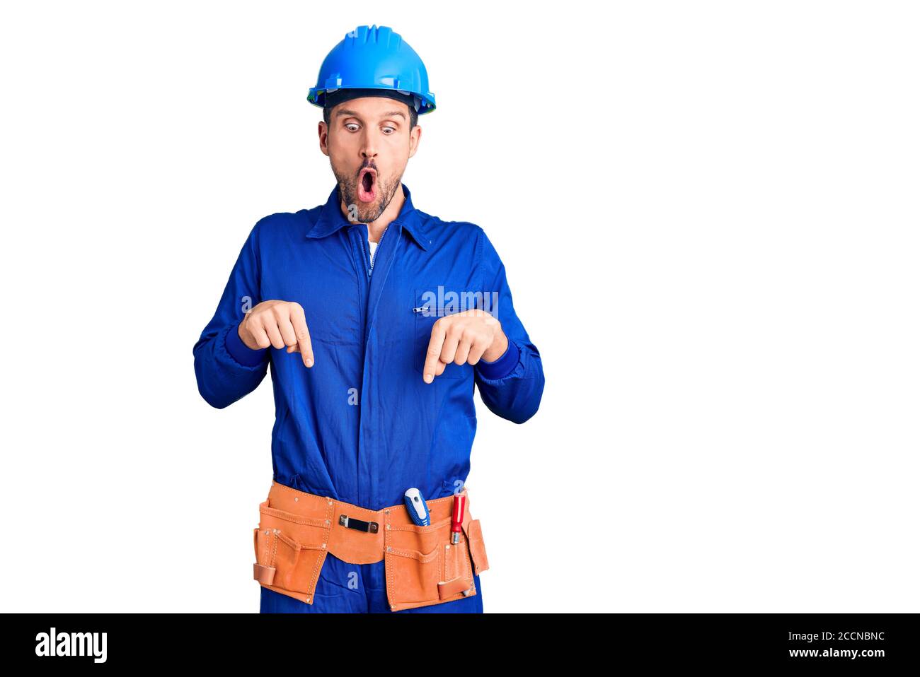Young handsome man wearing worker uniform and hardhat afraid and ...