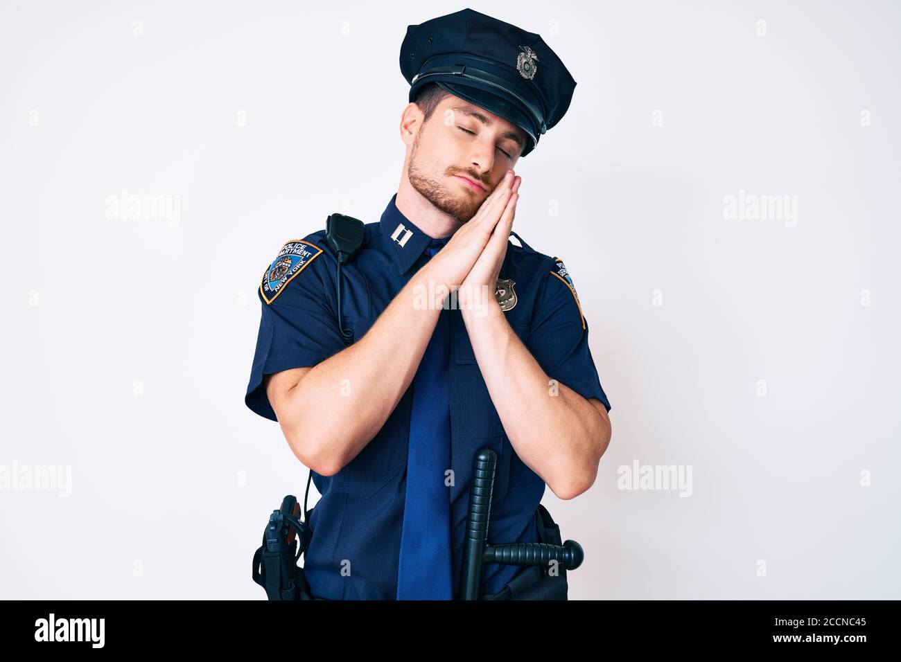 Young caucasian man wearing police uniform sleeping tired dreaming and ...