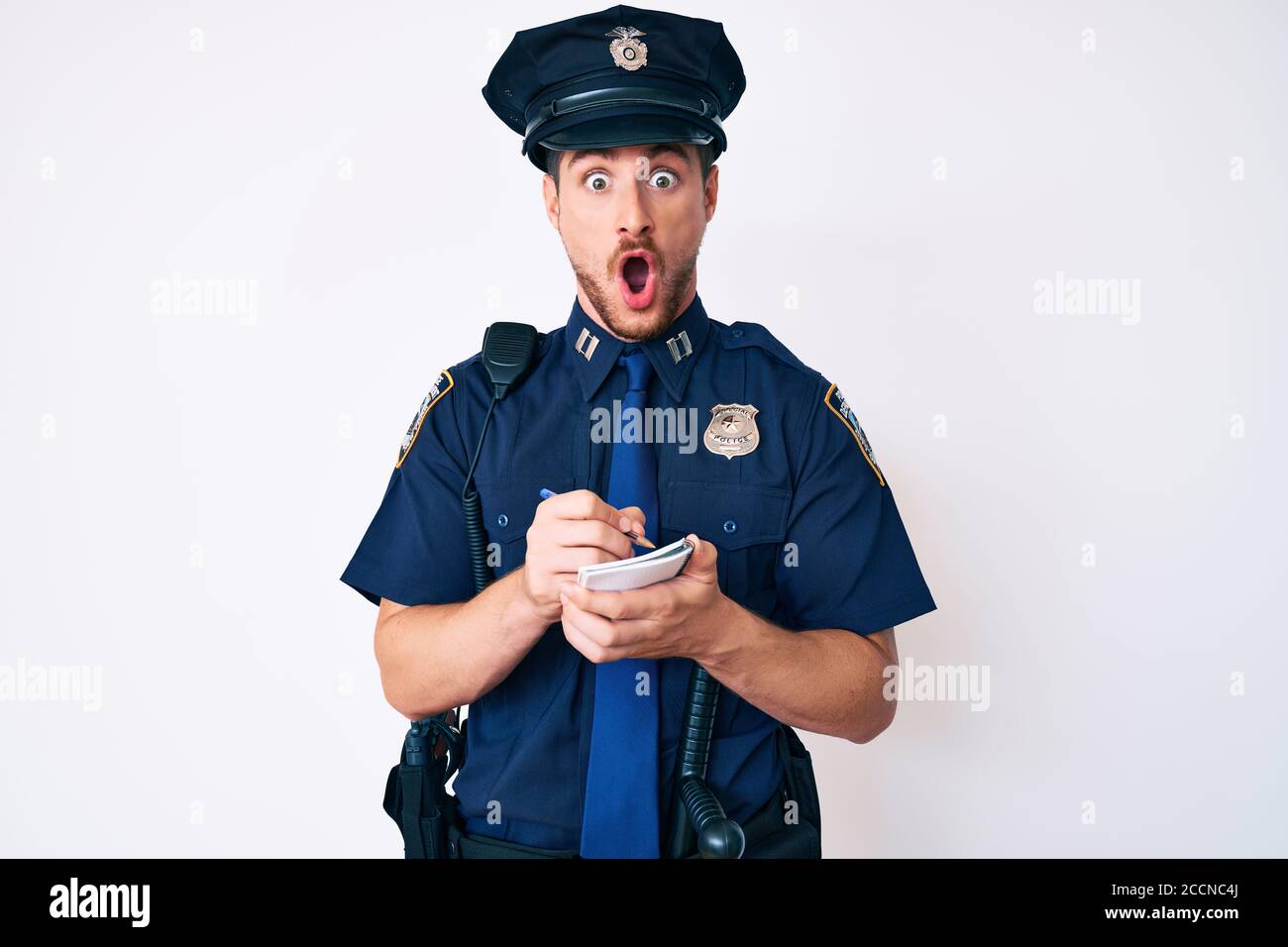 Young caucasian man wearing police uniform writing fine afraid and ...