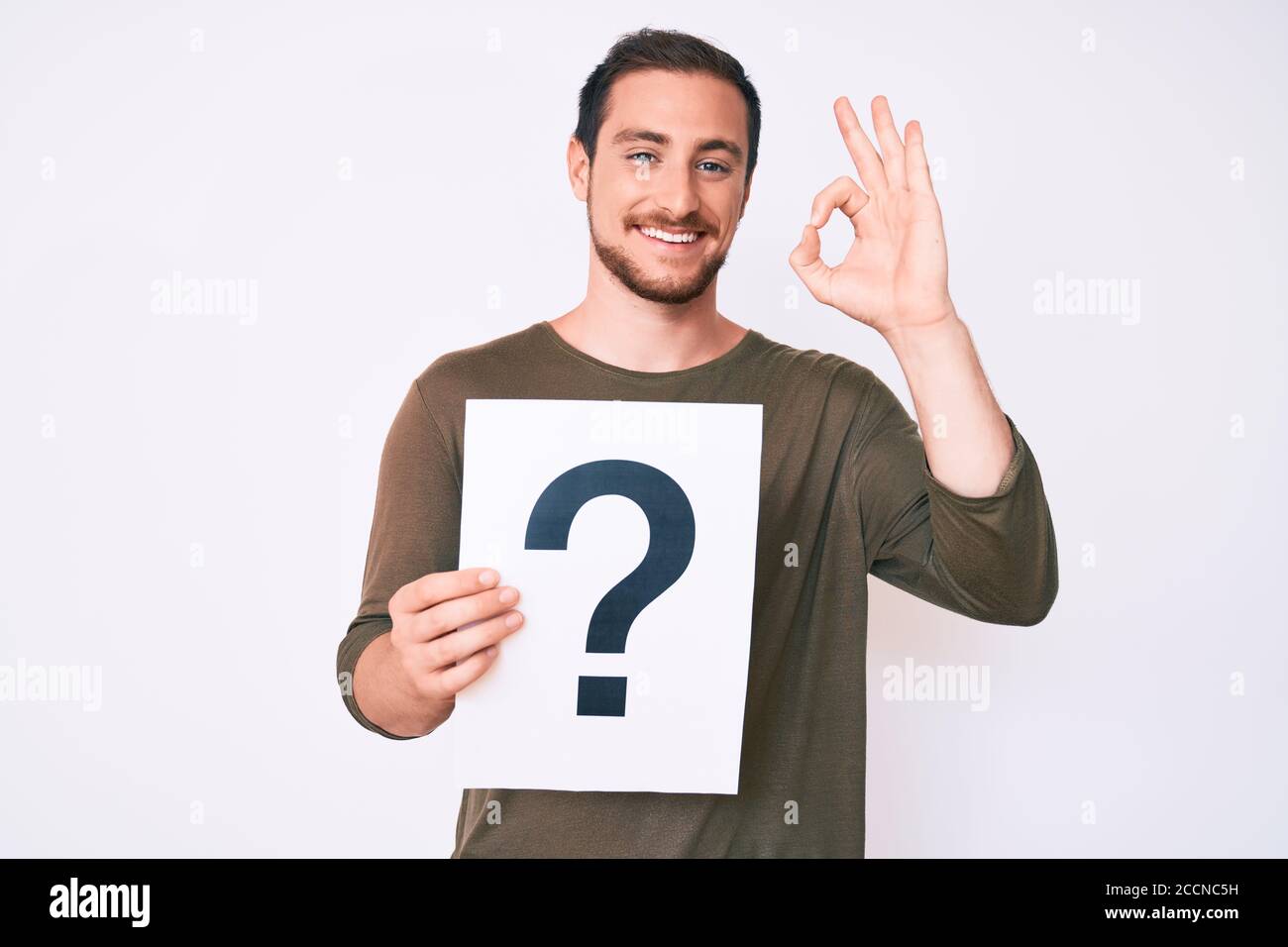 Young handsome man holding question mark doing ok sign with fingers ...