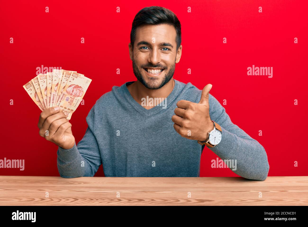 Handsome hispanic man holding mexican pesos smiling happy and positive ...
